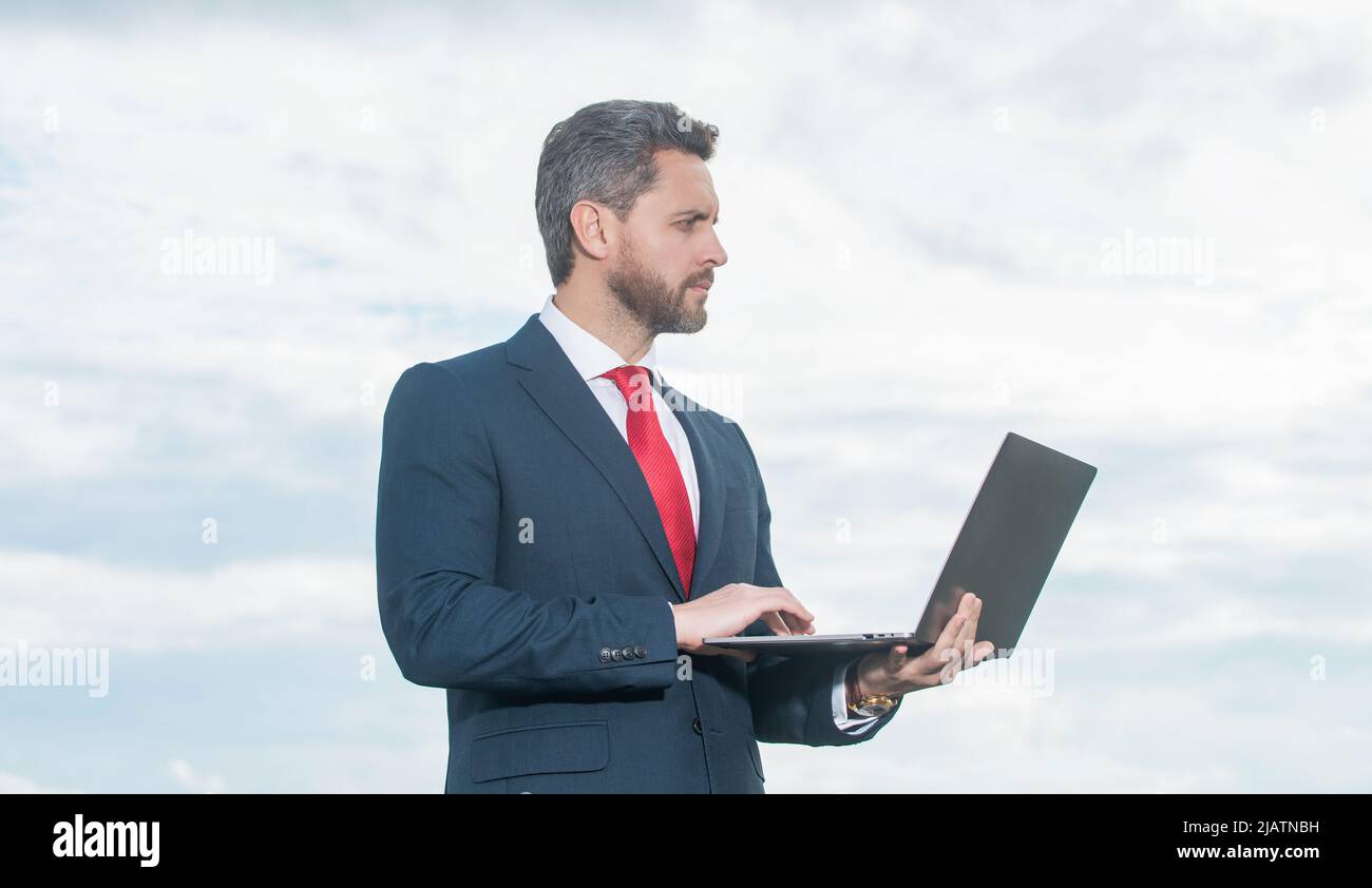 ceo in suit using laptop on sky background Stock Photo - Alamy