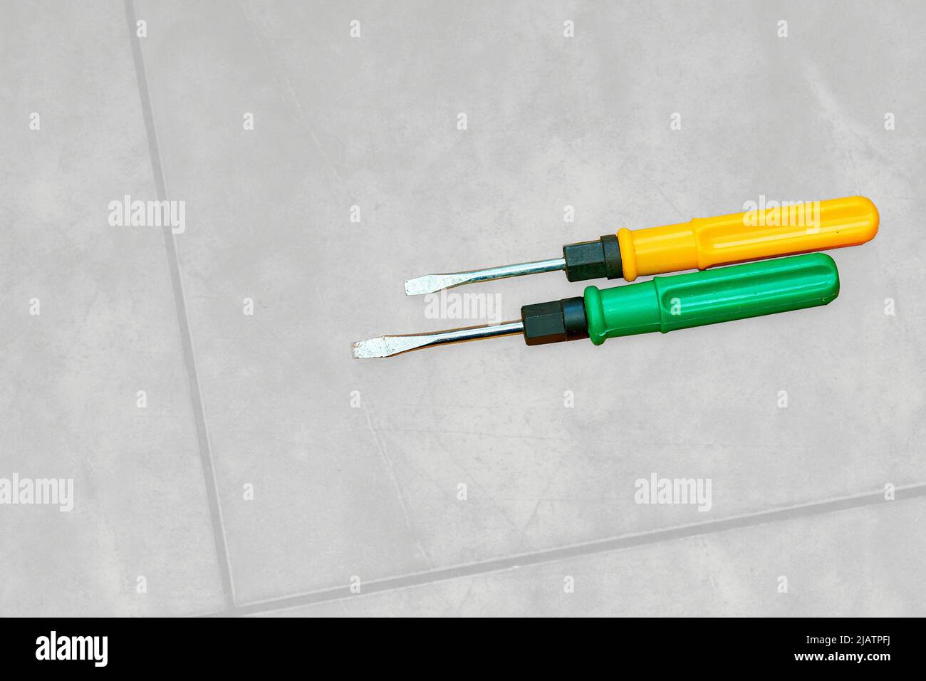 Green and orange screwdrivers on gray marble tiles Stock Photo - Alamy