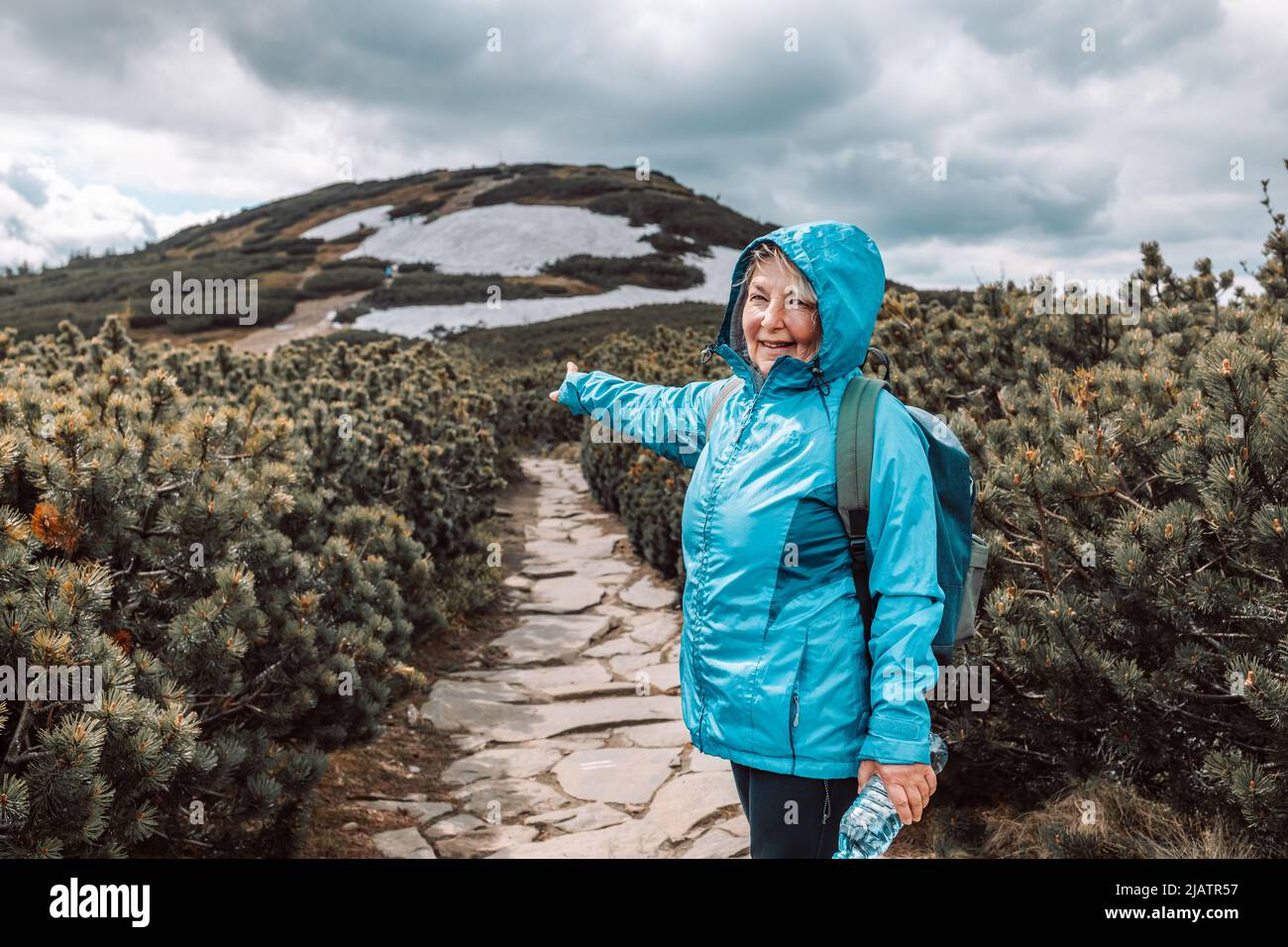 Senior caucasian 50s woman in sportswear shows the direction to the top ...