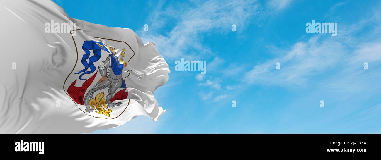 official flag of Odense , Denmark at cloudy sky background on sunset ...