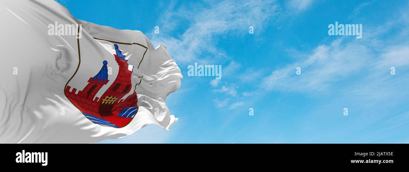 official flag of Randers , Denmark at cloudy sky background on sunset, panoramic view. Danish ...