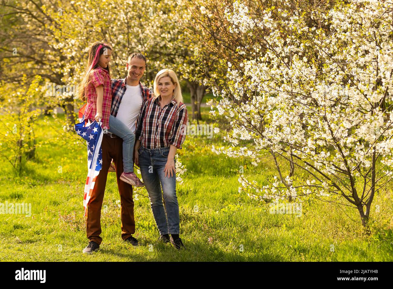 portrait of beautiful modern american family with USA flag outdoors ...