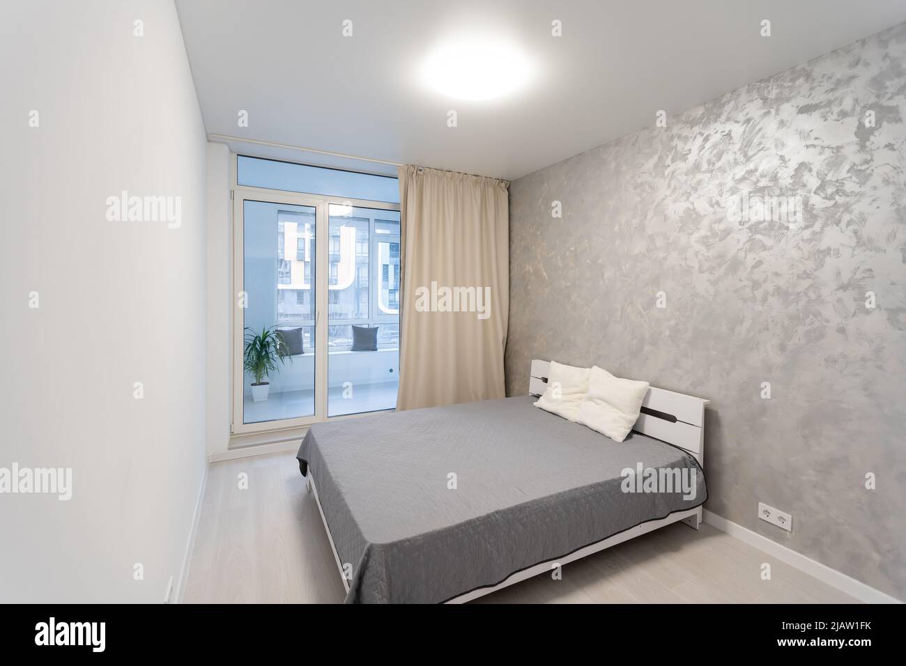 bed with gray linens in white interior Stock Photo - Alamy