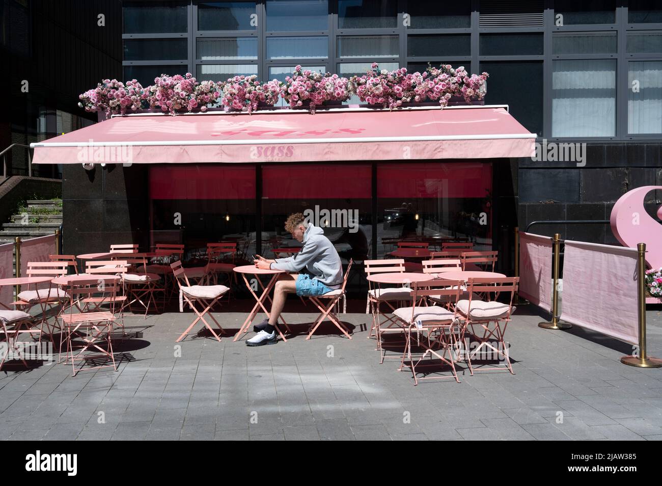 Liverpool, England, Uk. A young man sits alone at a pink painted bar ...