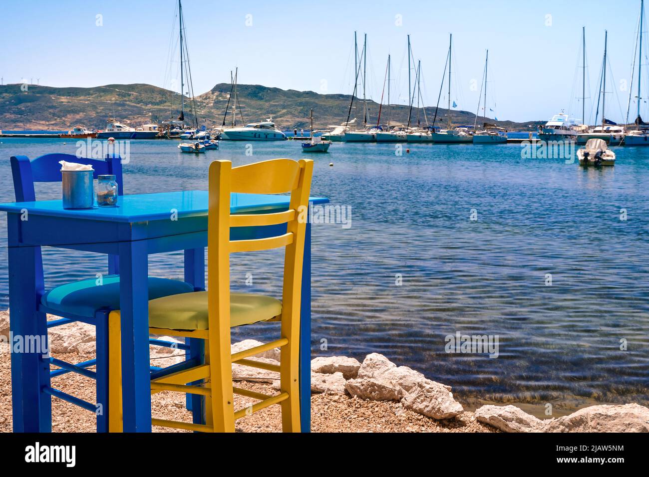 Colorful chair and table of Greek tavern by waterfront at day ...