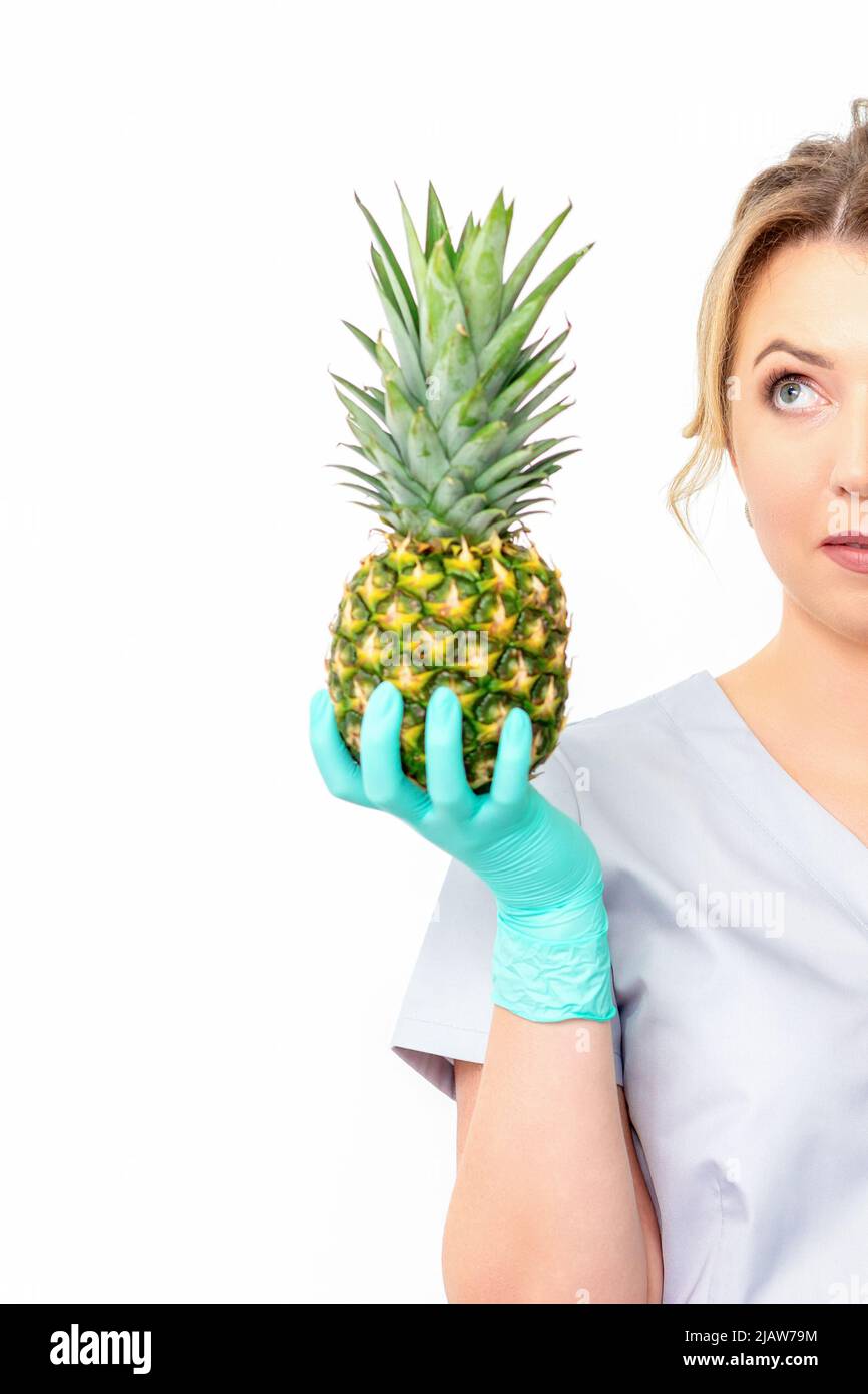 Young caucasian female doctor nutritionist holding fresh pineapple over ...