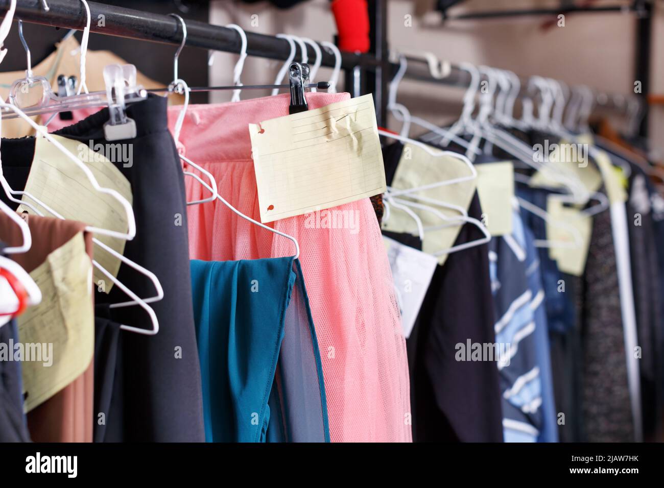 Clothes with tags on hangers in atelier Stock Photo - Alamy