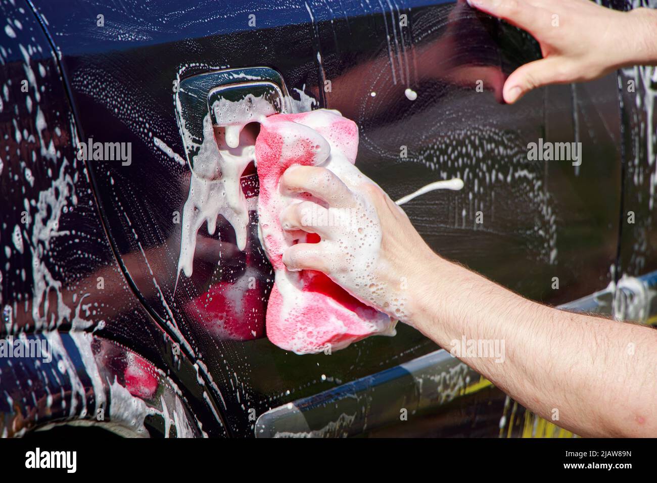 Man is washing car outside. Hand cleaning car in garage in front of ...