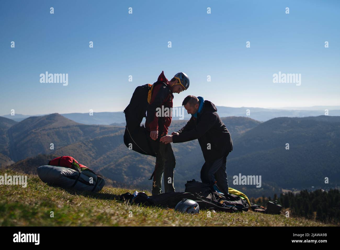 Man helping paragliding pilot to prepare for flight Stock Photo - Alamy