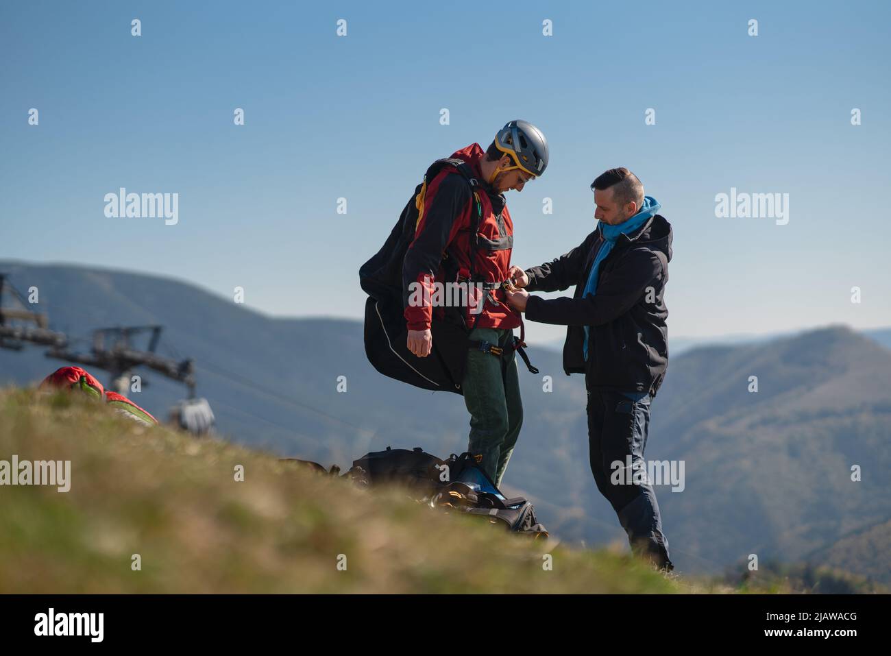 Man helping paragliding pilot to prepare for flight Stock Photo - Alamy