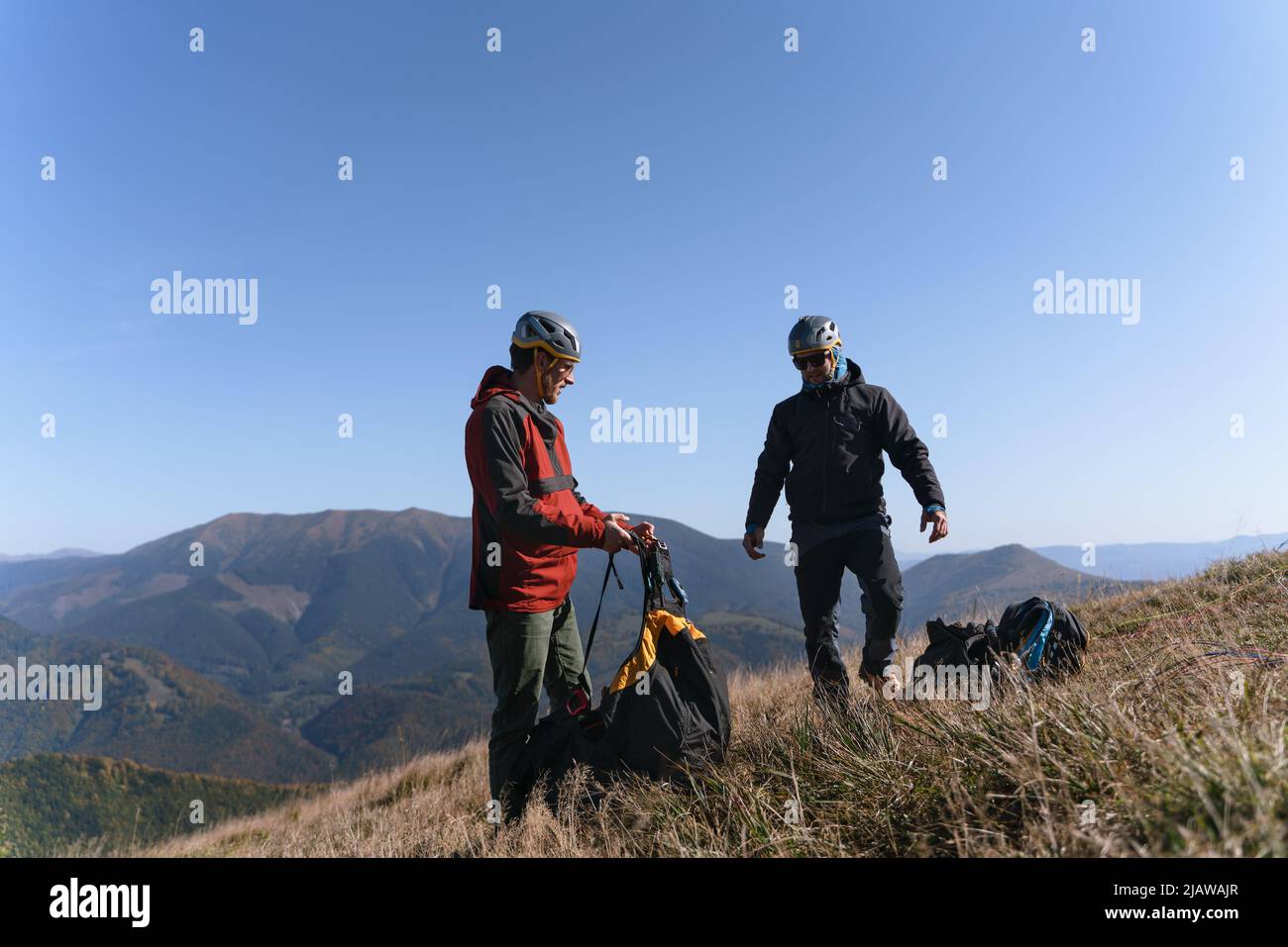 Man helping paragliding pilot to prepare for flight Stock Photo - Alamy