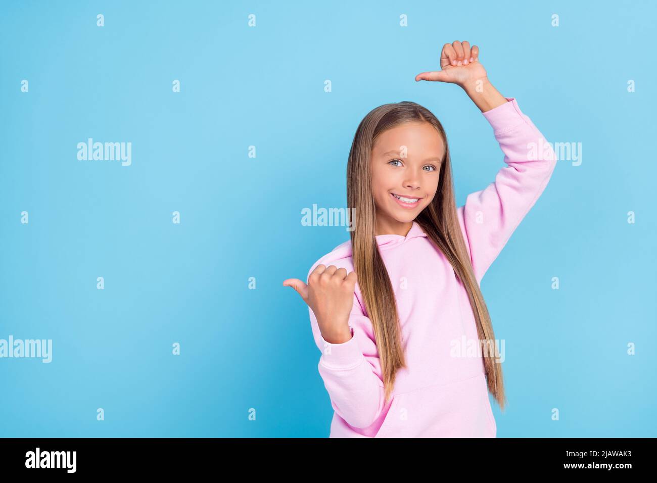 Photo of joyful nice happy positive small girl point finger thumb empty ...