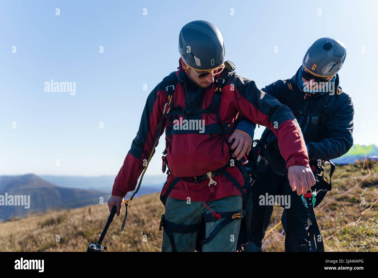 Man helping paragliding pilot to prepare for flight Stock Photo - Alamy