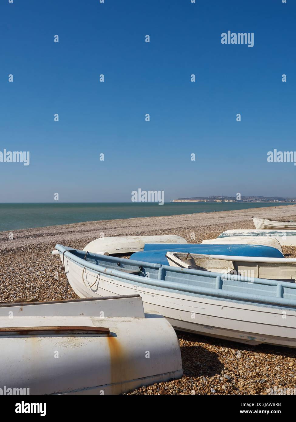 A collection of small timber boats pulled up onto the pebble beach at ...
