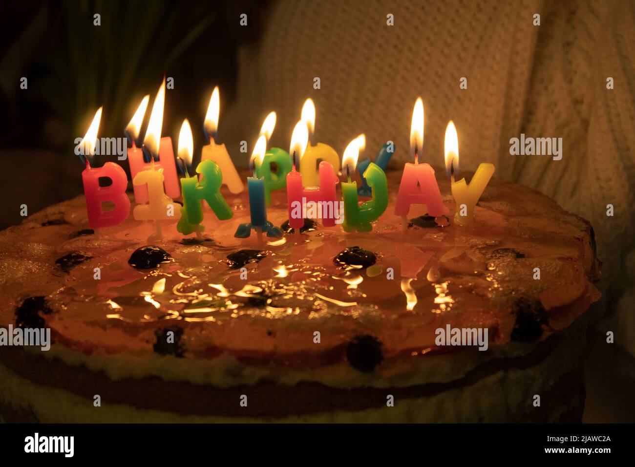 Multi-colored candles in the form of letters on a birthday cake ...