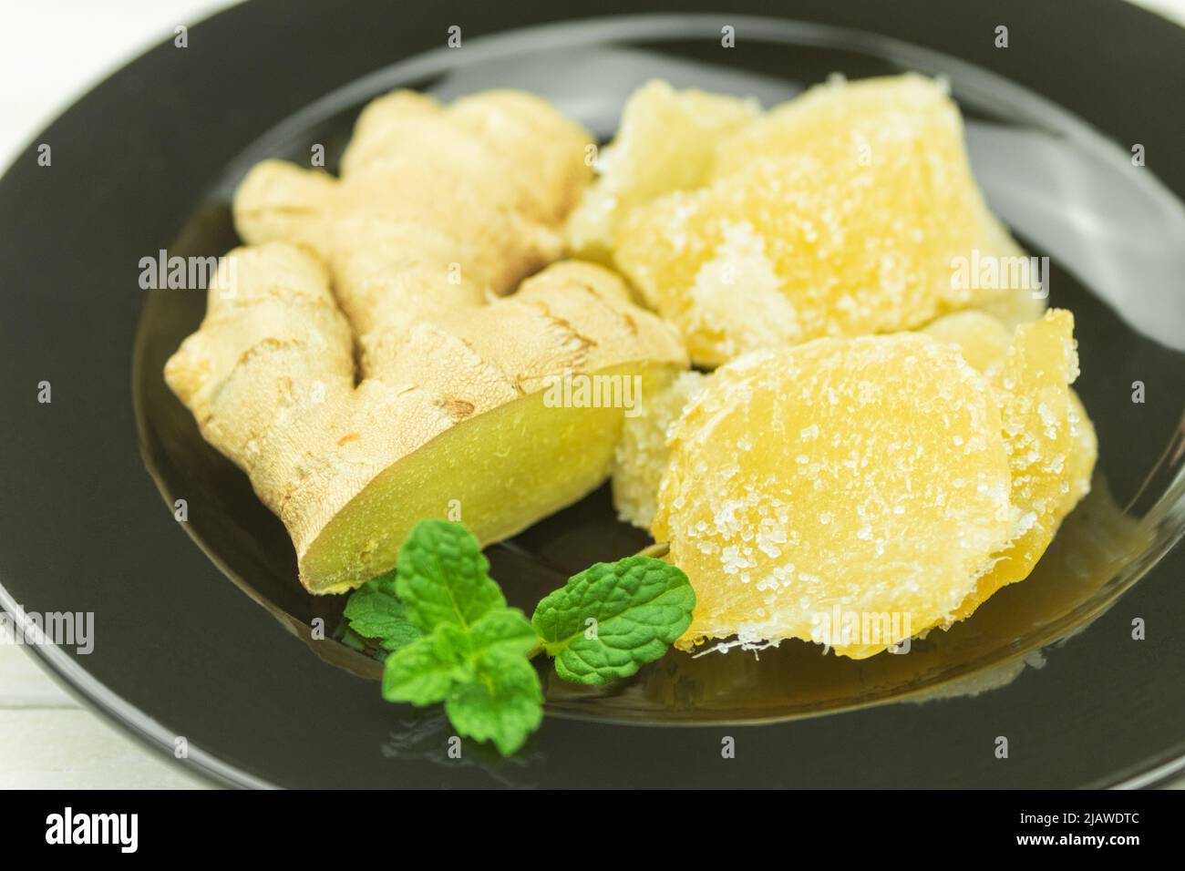 Fresh ginger root and candied ginger in sugar. Close-up of candied ...
