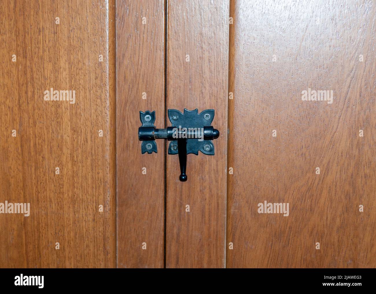 Black metal deadbolt on brown wooden door, closed without a key Stock ...