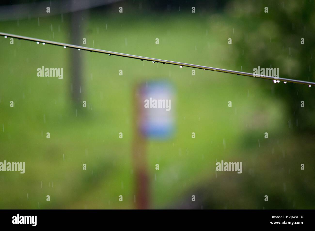 Rainsdrops on telephone wire with English roadside bus stop in ...