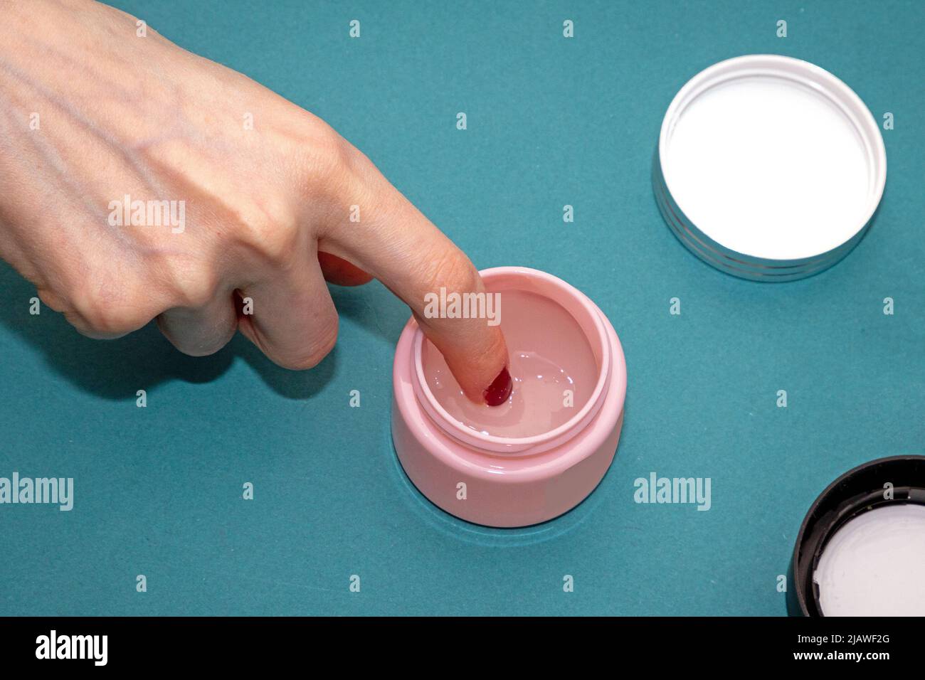 Female finger inside open beauty face cream jar Stock Photo - Alamy