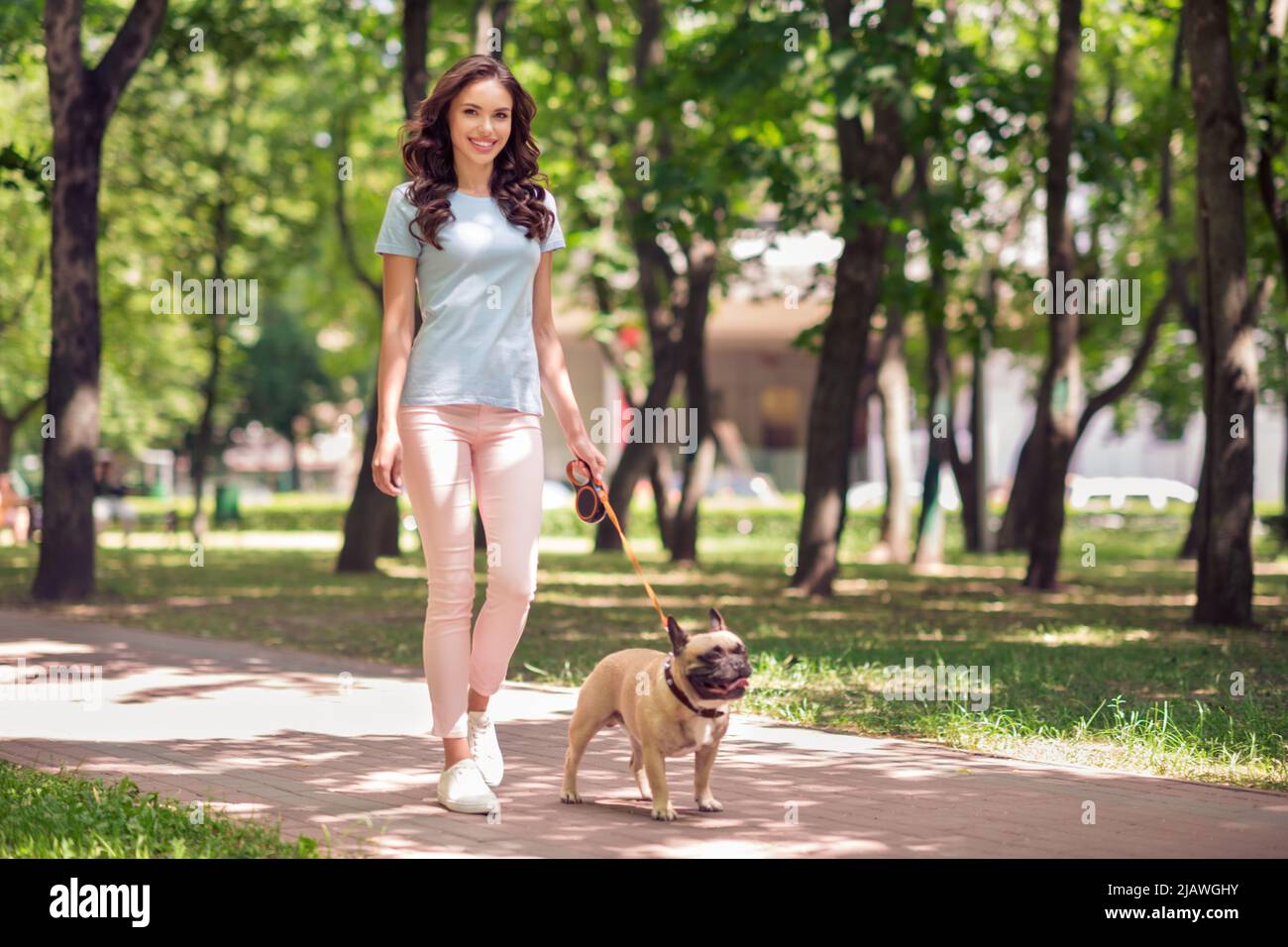 Full length photo of cheerful young happy woman hold hand leash walk ...