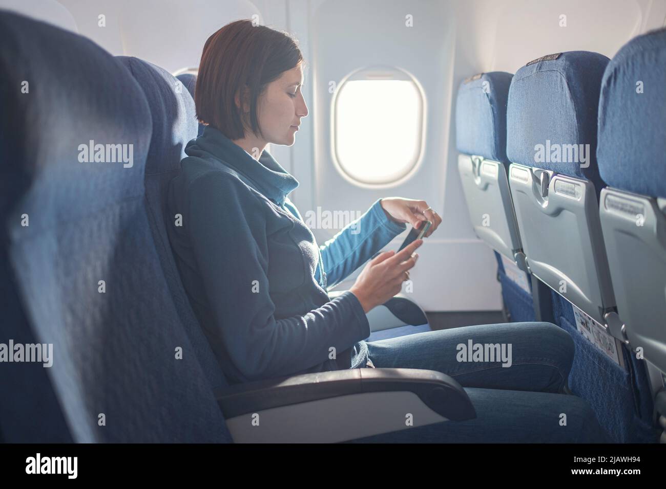 Young beautiful woman sitting at window of plane during the flight ...