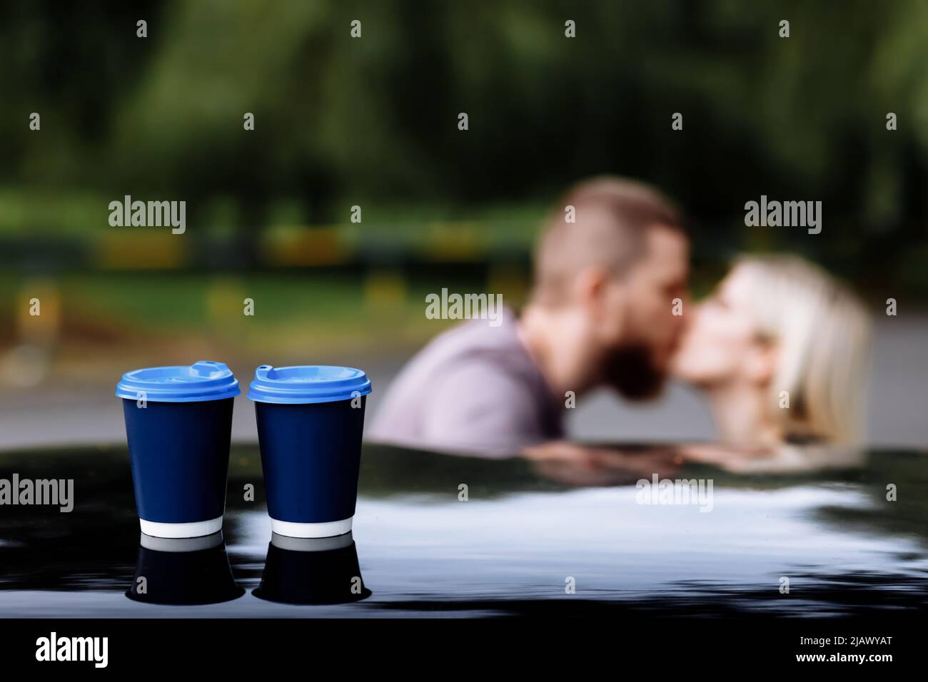 two cups of coffee or tea on car roof on couple background outdoors ...