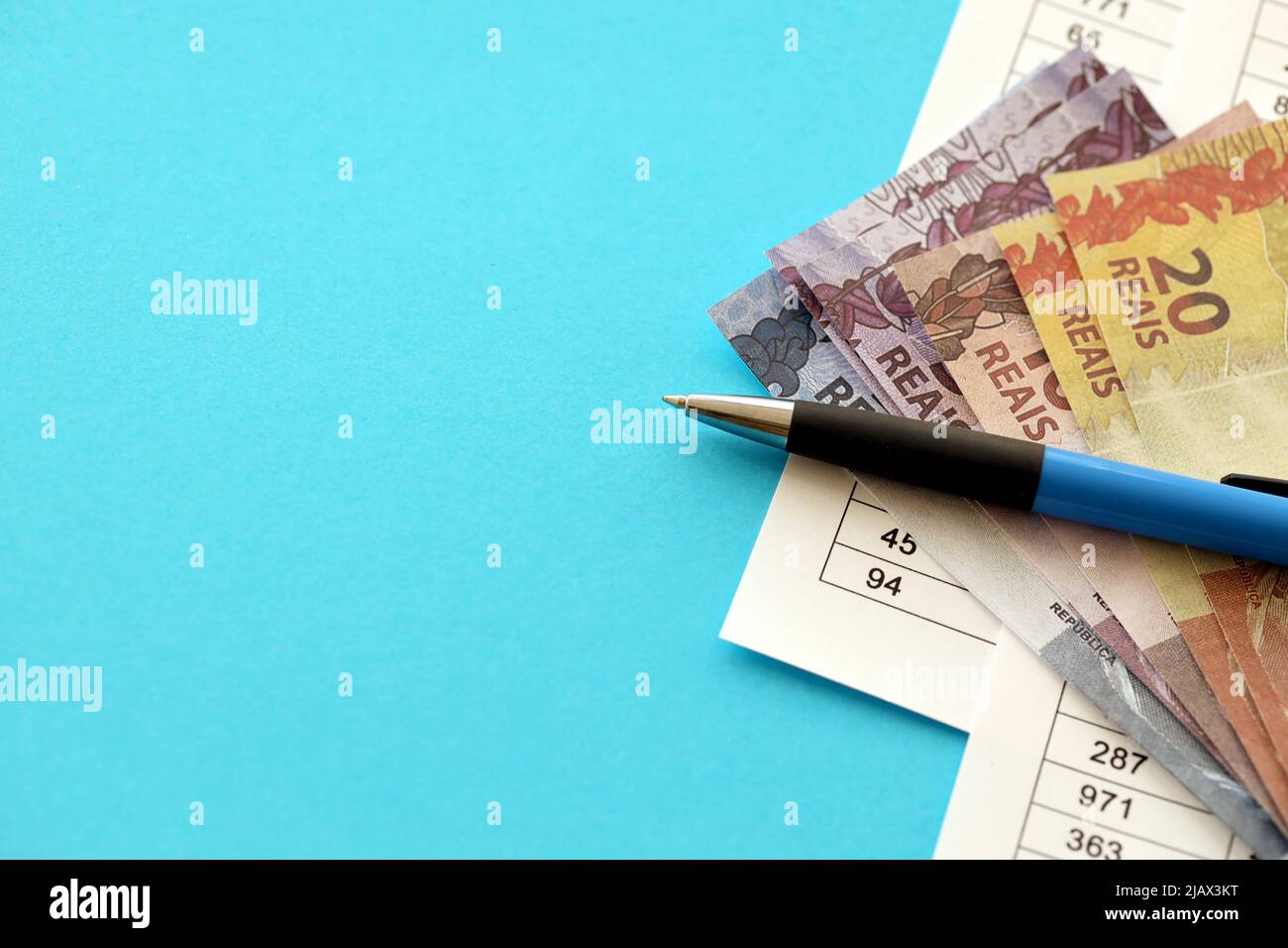 Pen with Brazilian money bills on documents with calculations table ...