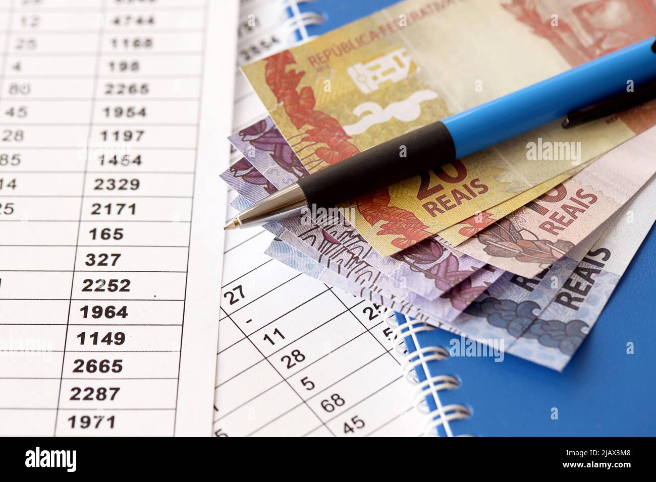 Pen with Brazilian money bills on documents with calculations table ...