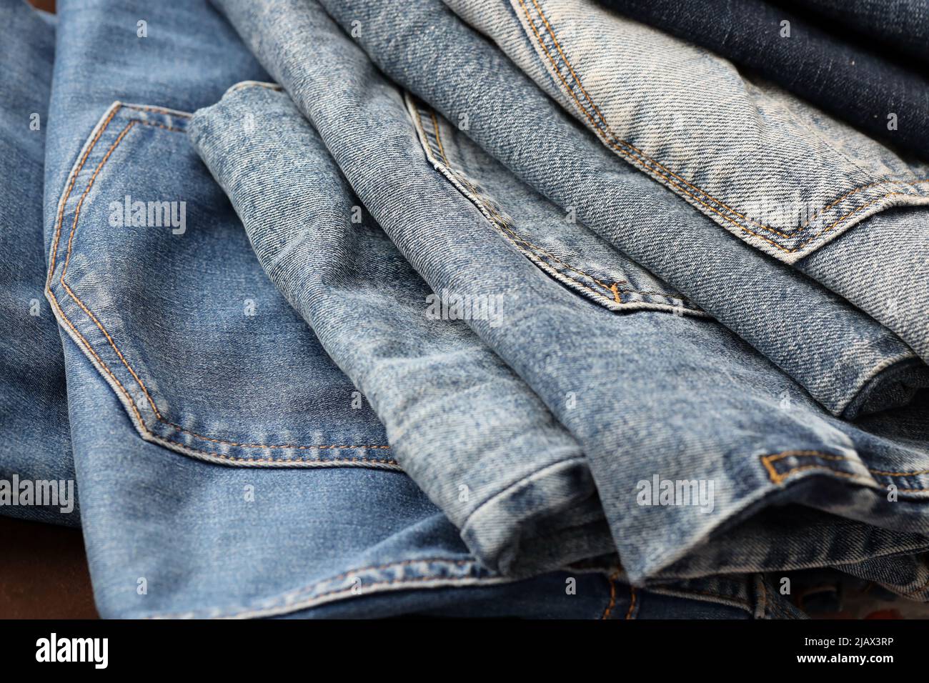 Many jeans in stack in wardrobe room. Row of pants denim jeans in ...