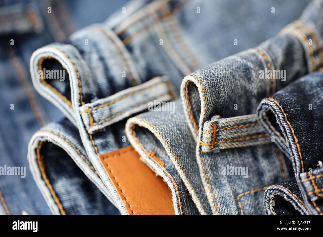 Many jeans in stack in wardrobe room. Row of pants denim jeans in ...