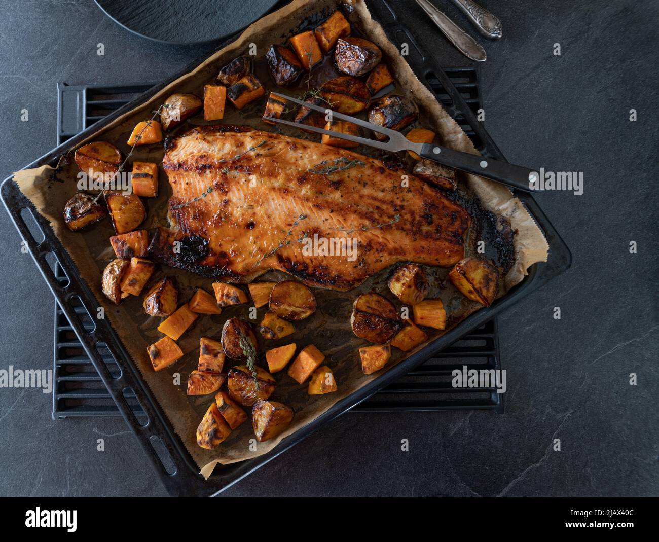 Caramelized half salmon fillet with roasted potatoes and herbs on a ...