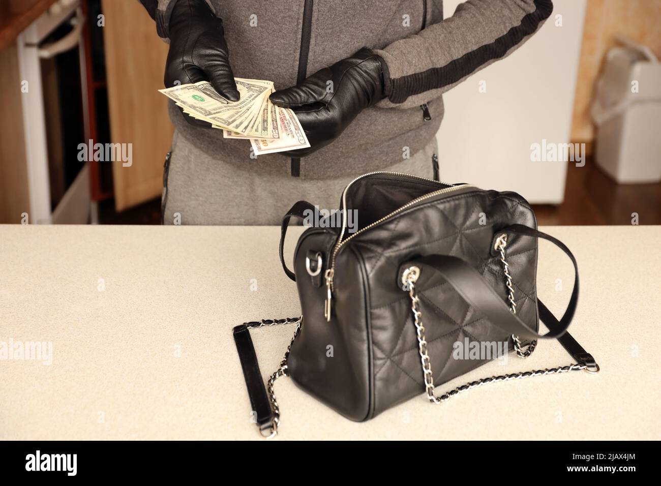 Robber in black outfit and gloves see in opened stolen women bag. The ...