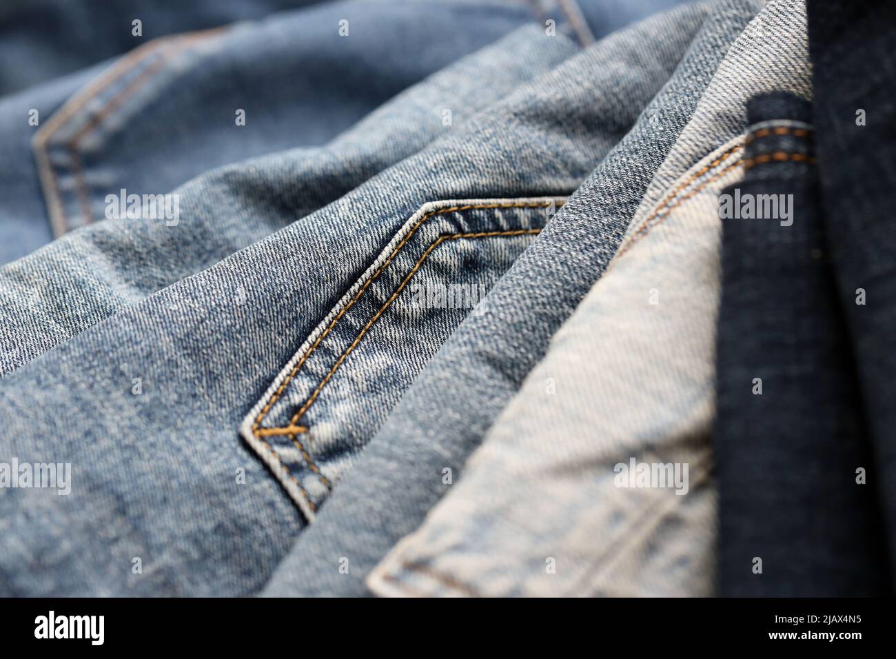 Many jeans in stack in wardrobe room. Row of pants denim jeans in ...