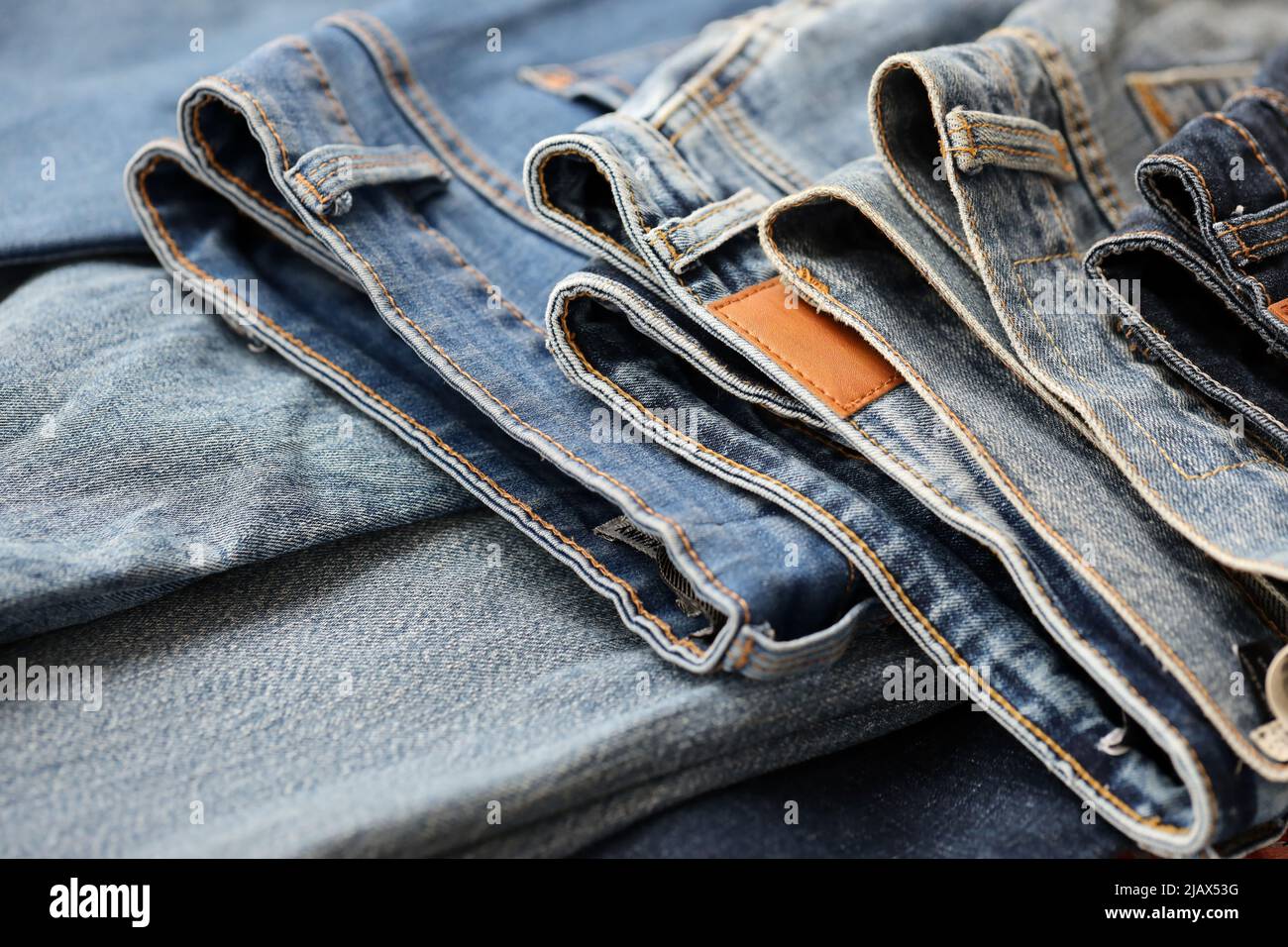 Many jeans in stack in wardrobe room. Row of pants denim jeans in ...