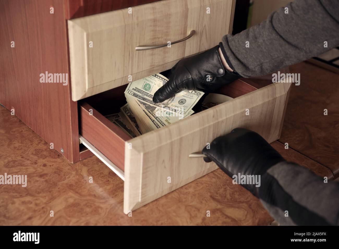 Robber in black outfit and gloves see in opened shelf in kitchen. The ...