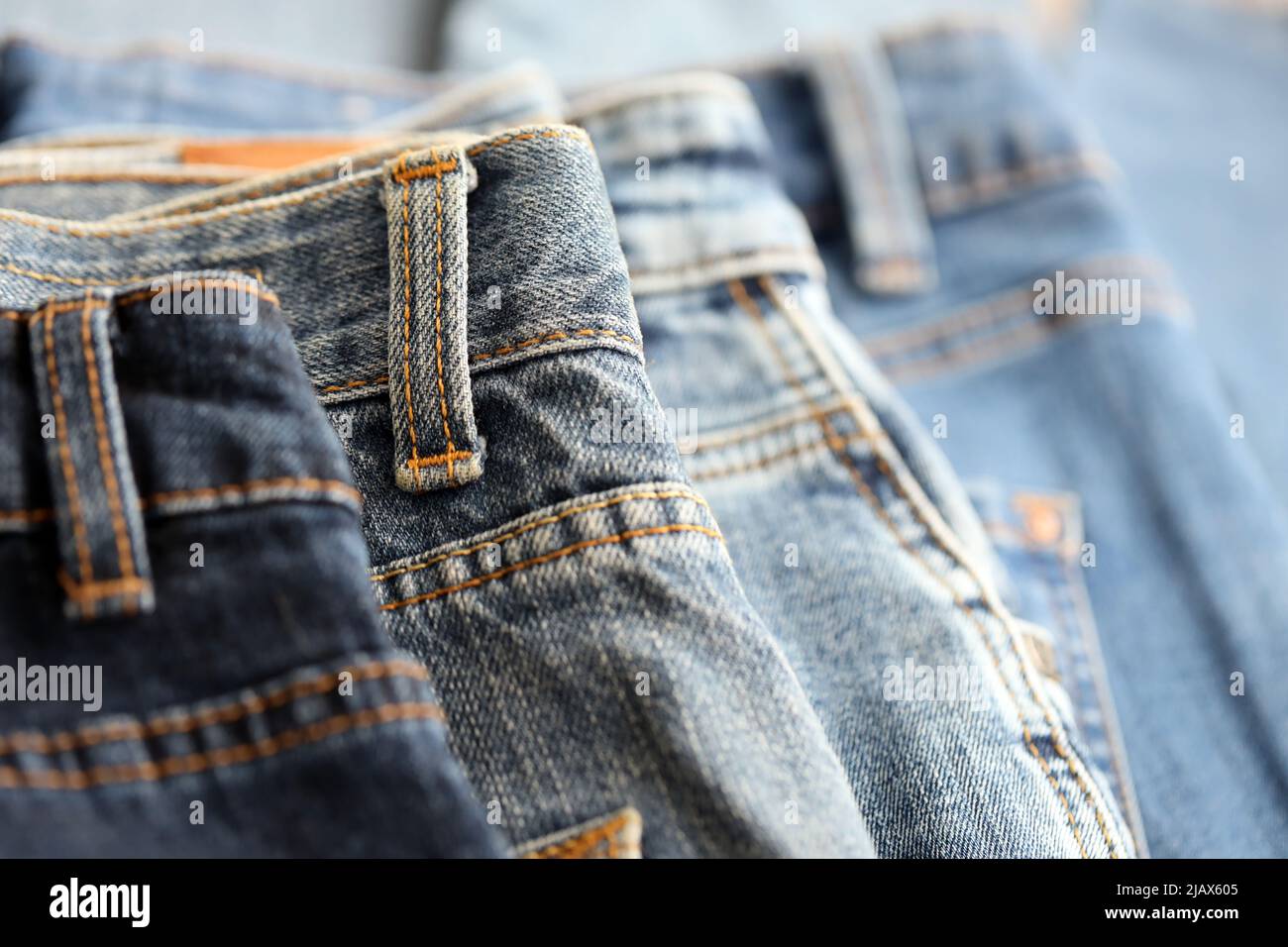 Many jeans in stack in wardrobe room. Row of pants denim jeans in ...