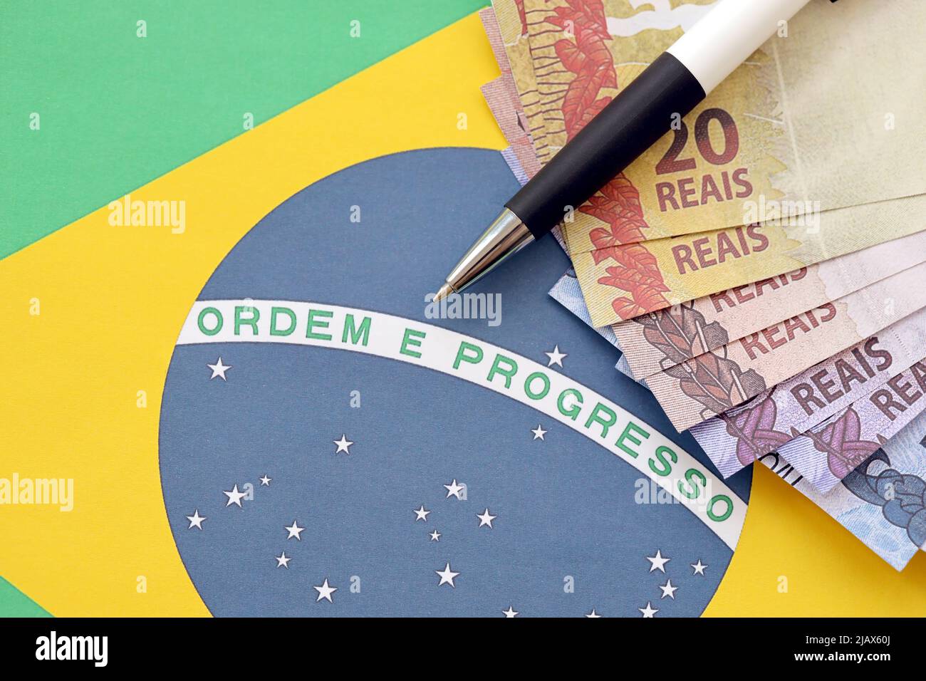 Pen with Brazilian money bills on flag of Brazil republic. Concept of ...