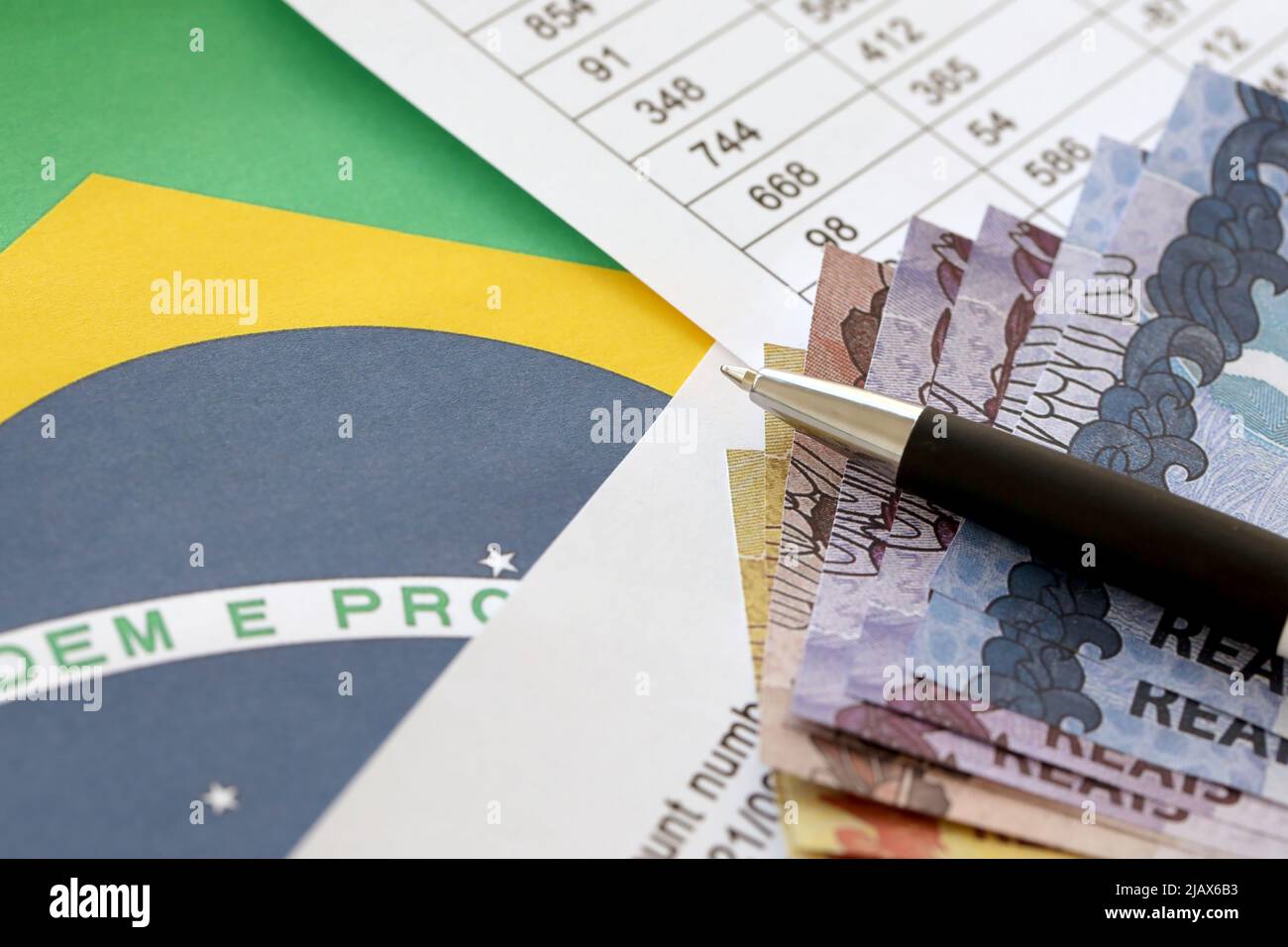 Pen with Brazilian money bills on flag of Brazil republic. Concept of ...