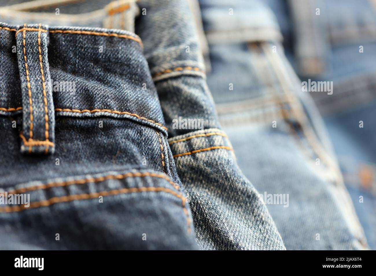 Many jeans in stack in wardrobe room. Row of pants denim jeans in ...