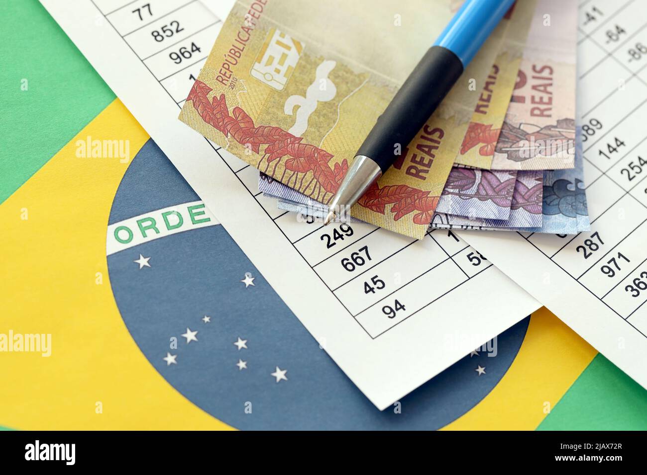Pen with Brazilian money bills on flag of Brazil republic. Concept of ...