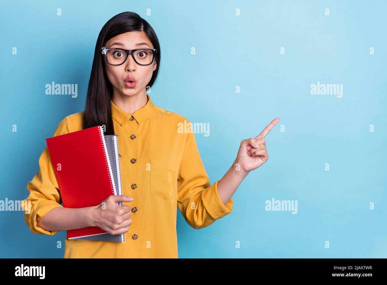 Photo of young asian girl amazed shocked hold notebook study point finger empty space decision ...