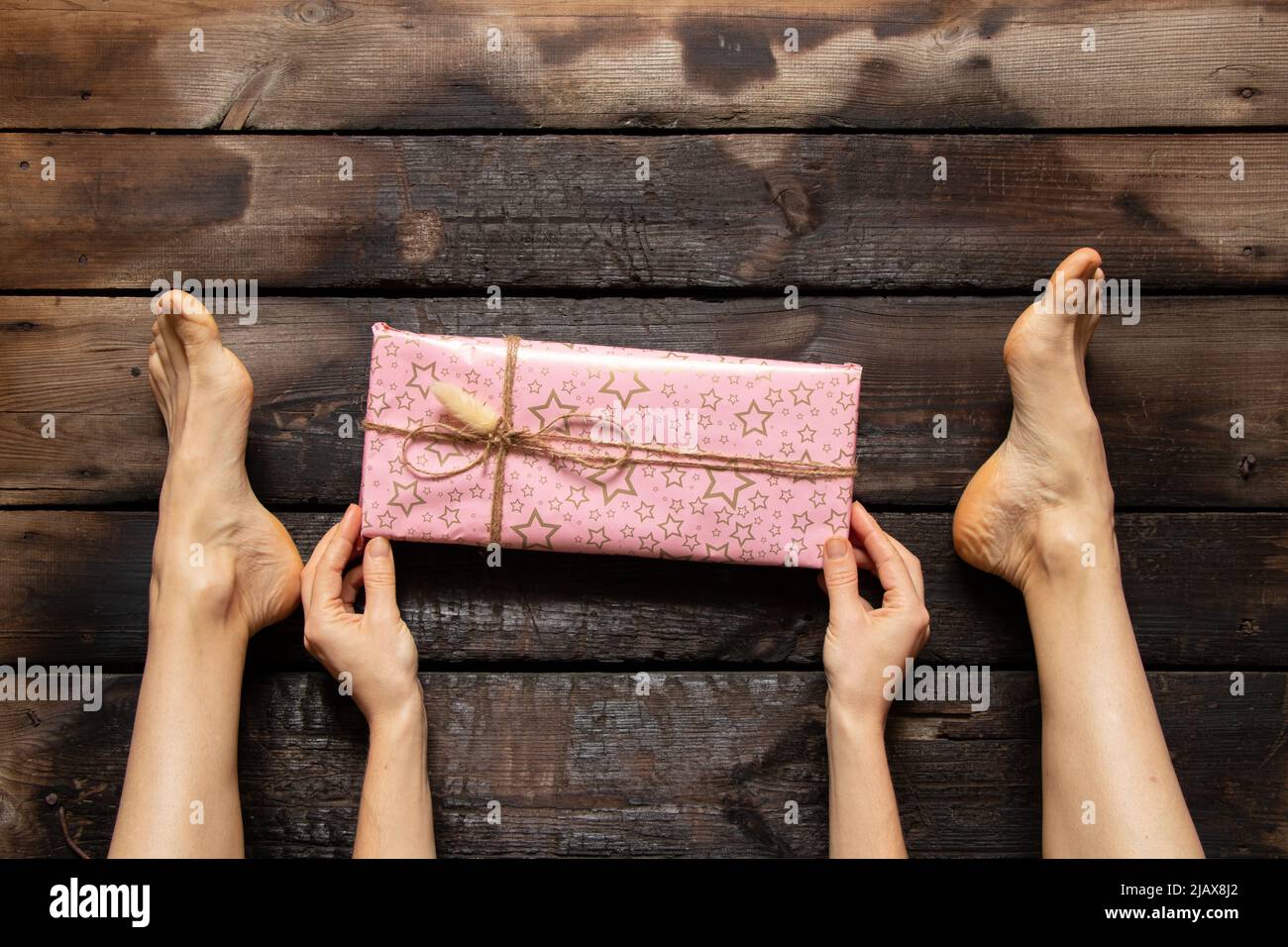 girl unfolds a birthday present on the wooden floor of the house ...