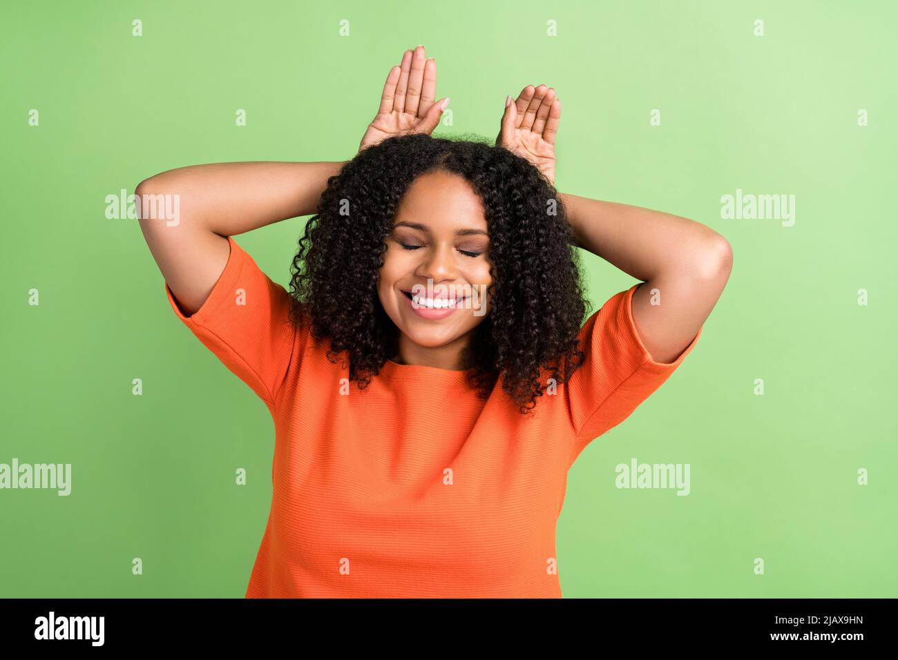 Photo of young african woman happy positive smile show arms rabbit ears ...