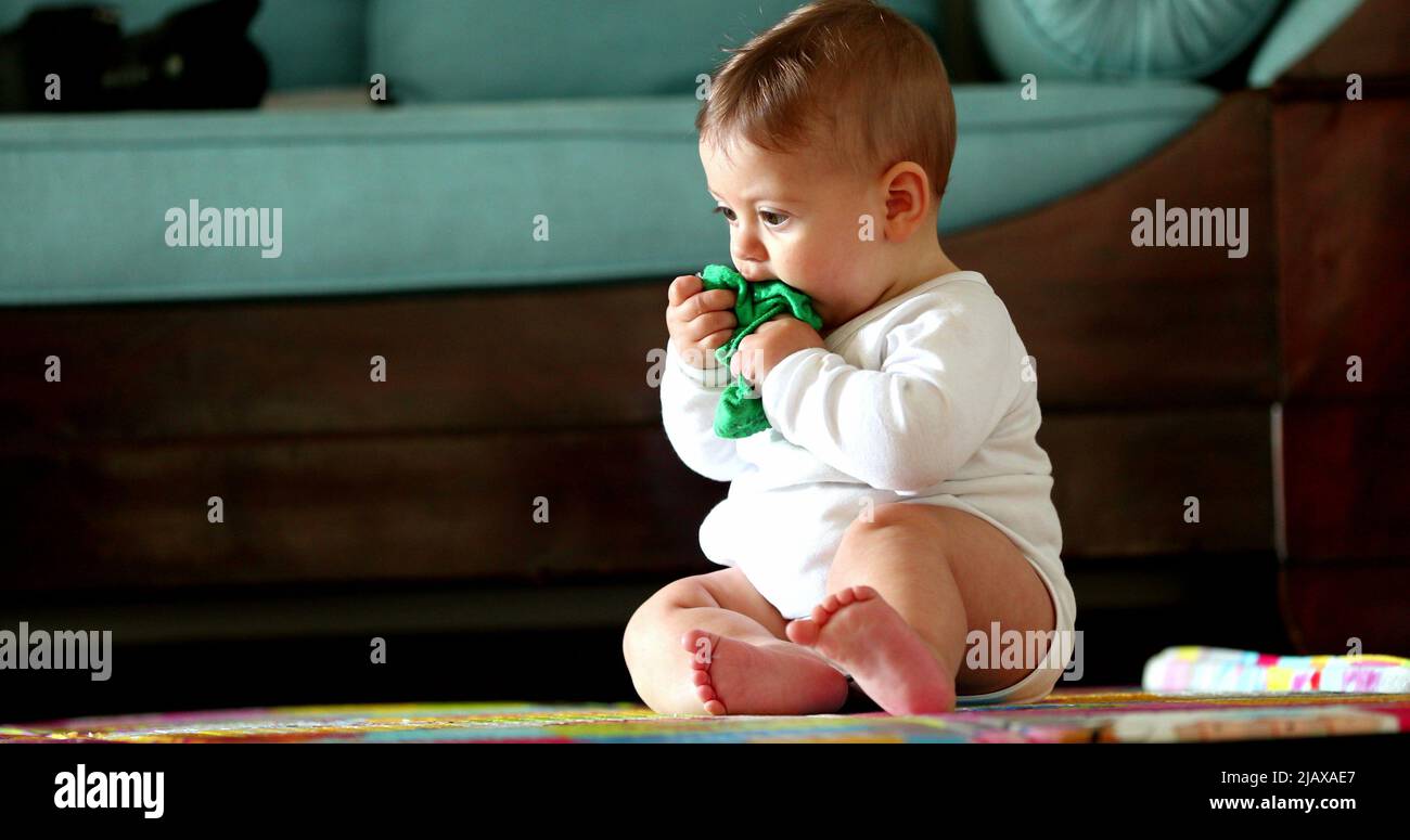 Cute baby infant playing casually in the living-room on top of play mat ...