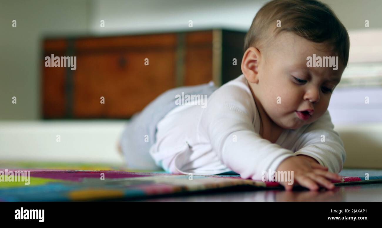 Cute baby lying on floor touching play carpet Stock Photo - Alamy