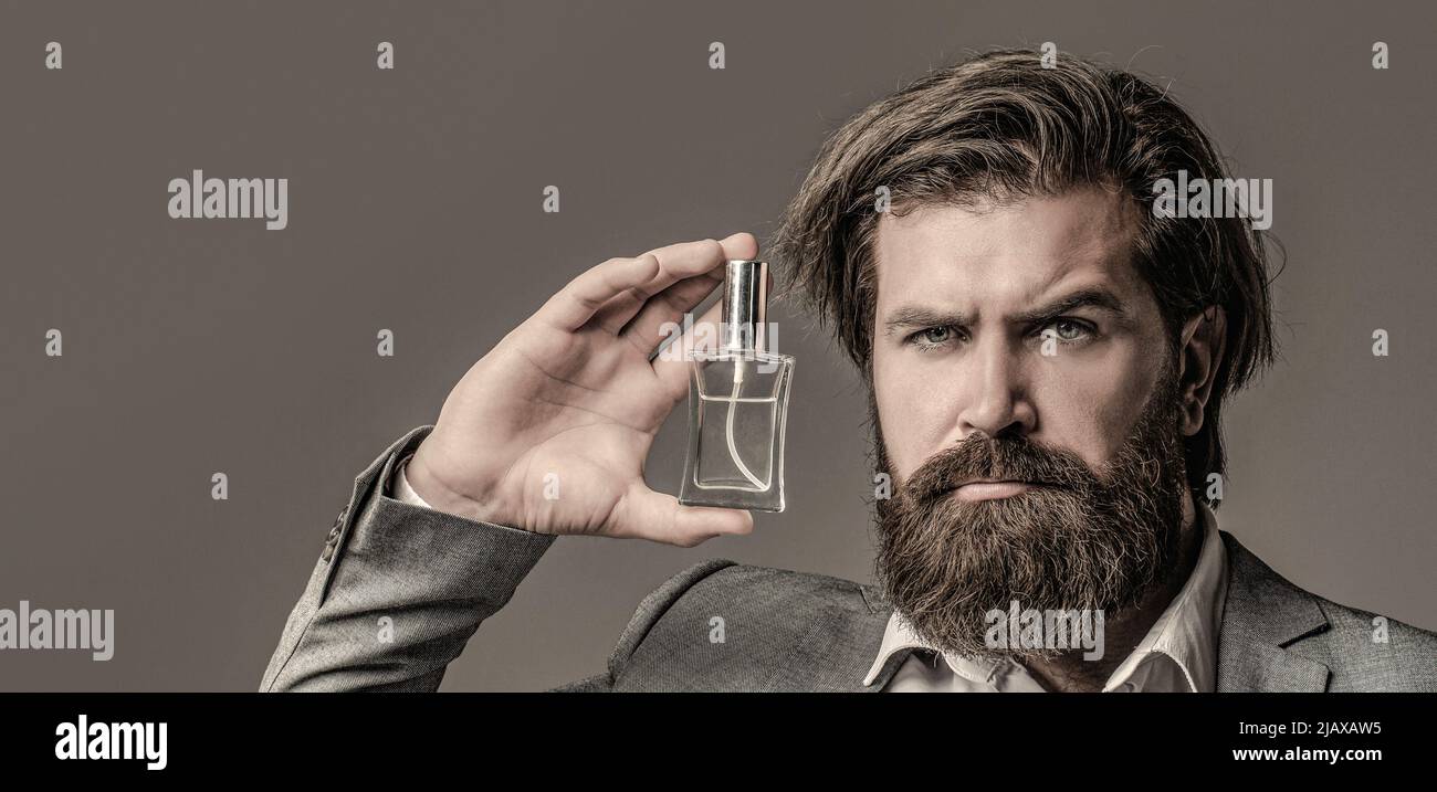 Masculine perfume, bearded man in a suit. Male holding up bottle of ...