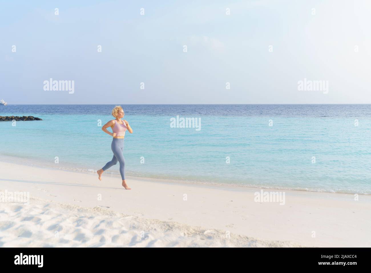 Athletic woman jogging on the beach Stock Photo - Alamy