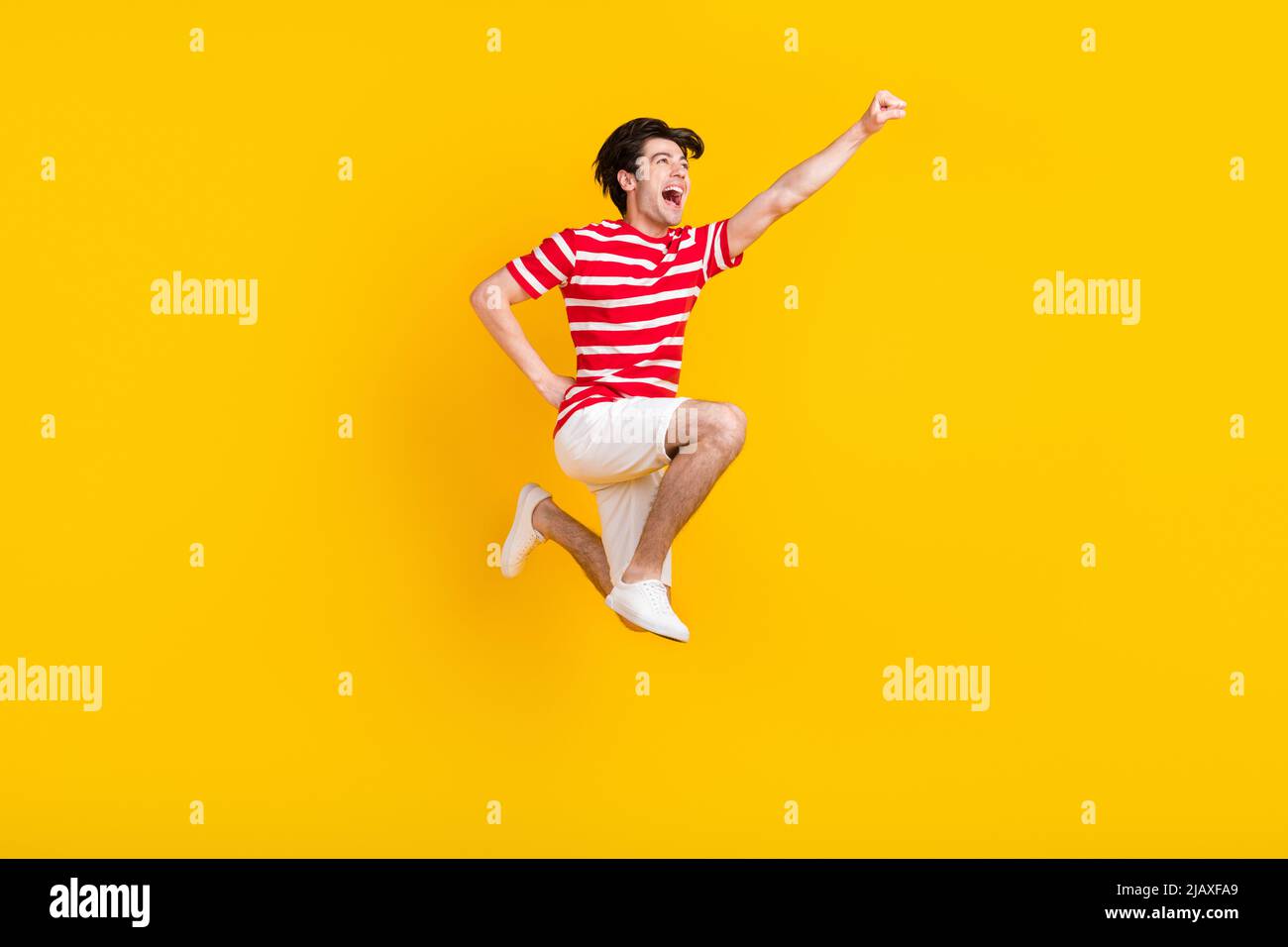 Full size photo of happy joyful young raise hand super hero jump up ...