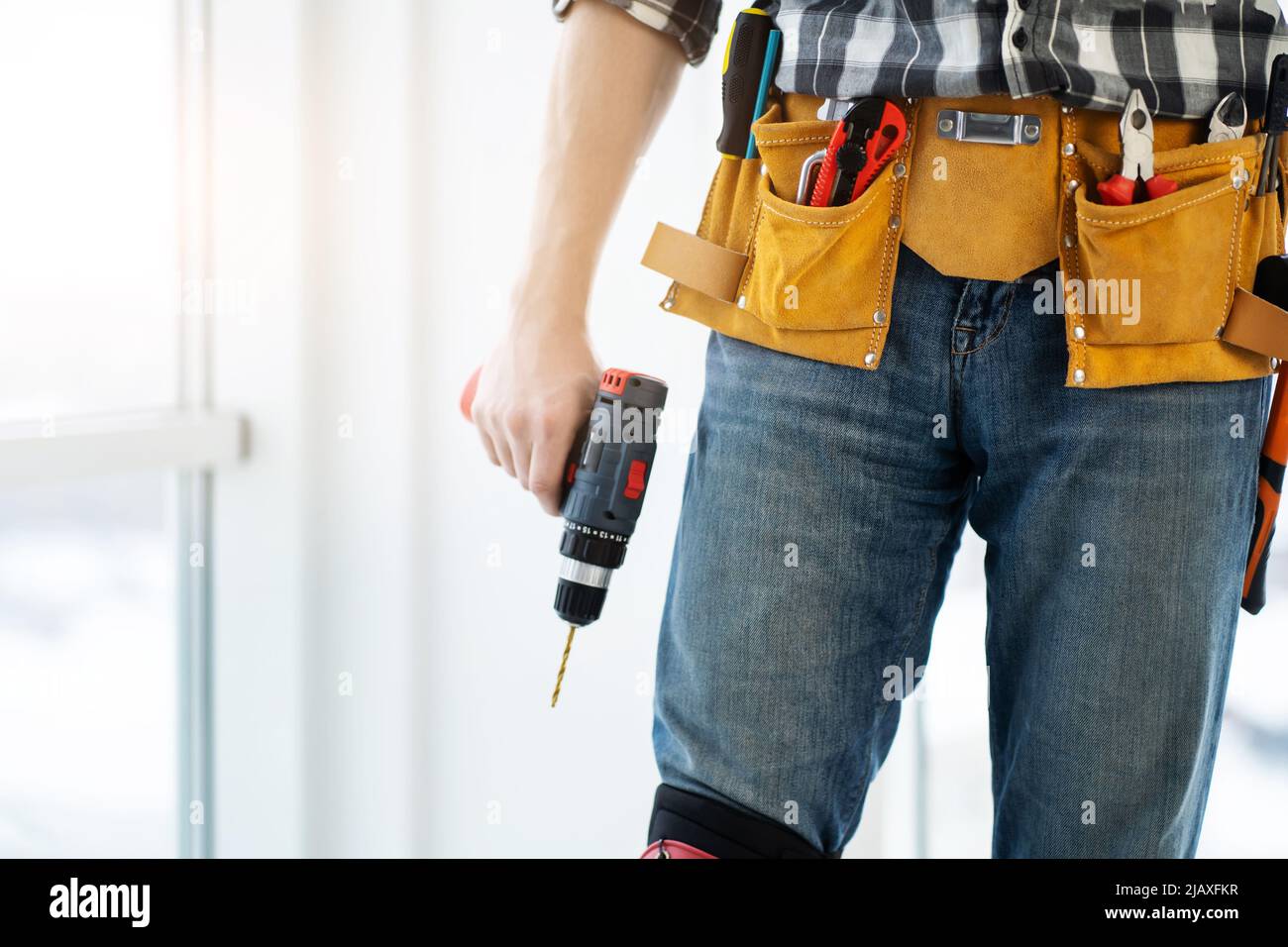 Worker wearing tool belt and holding drill Stock Photo - Alamy