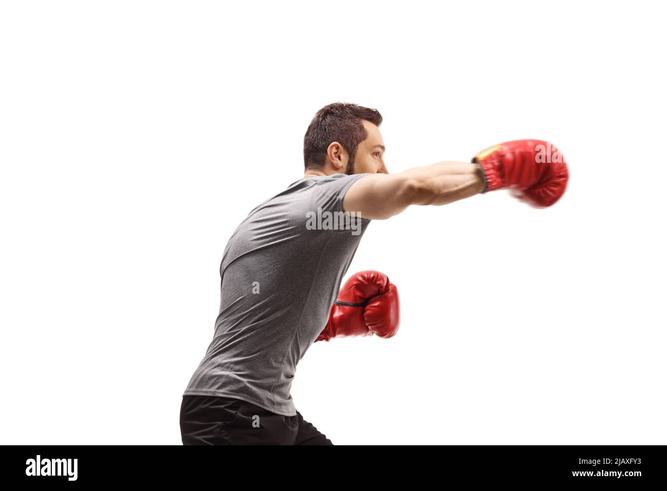 Profile shot of a young man punching with boxing gloves isolated on ...